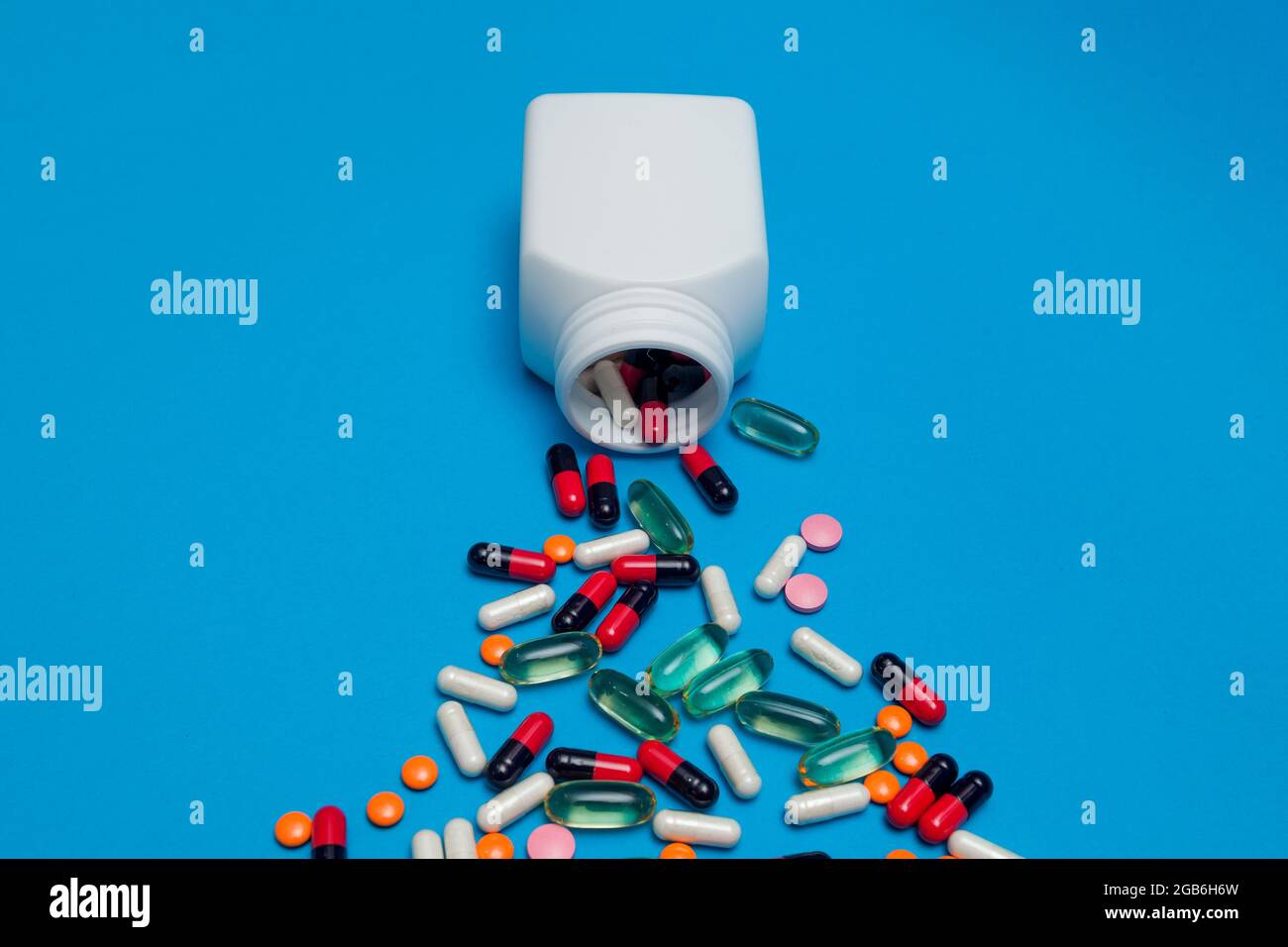 multicolored pills falling out of a jar on a blue background Stock ...