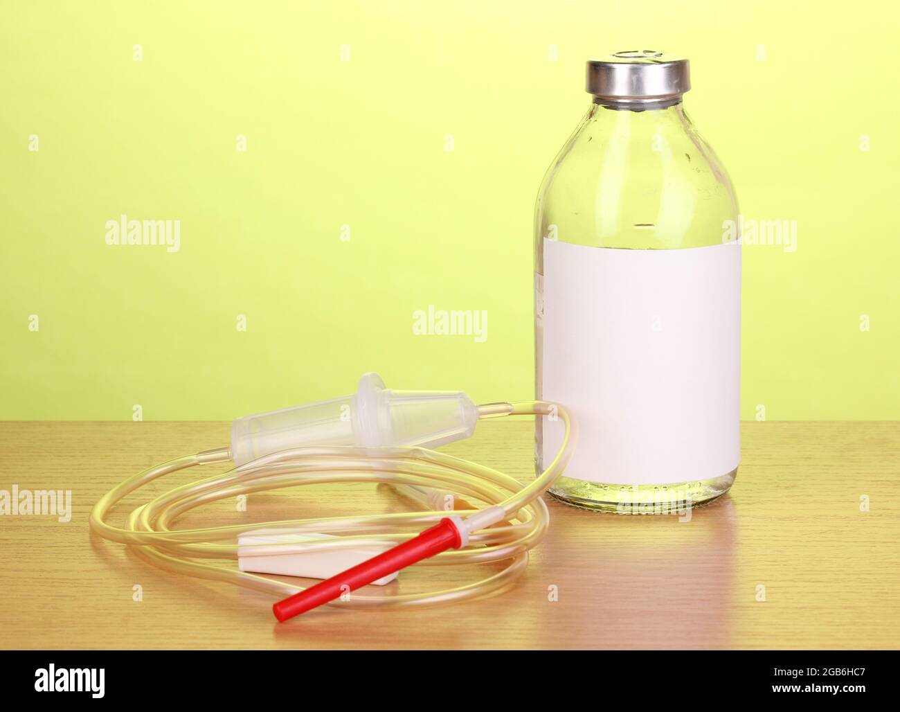 Bottle of intravenous antibiotics and plastic infusion set on wooden ...