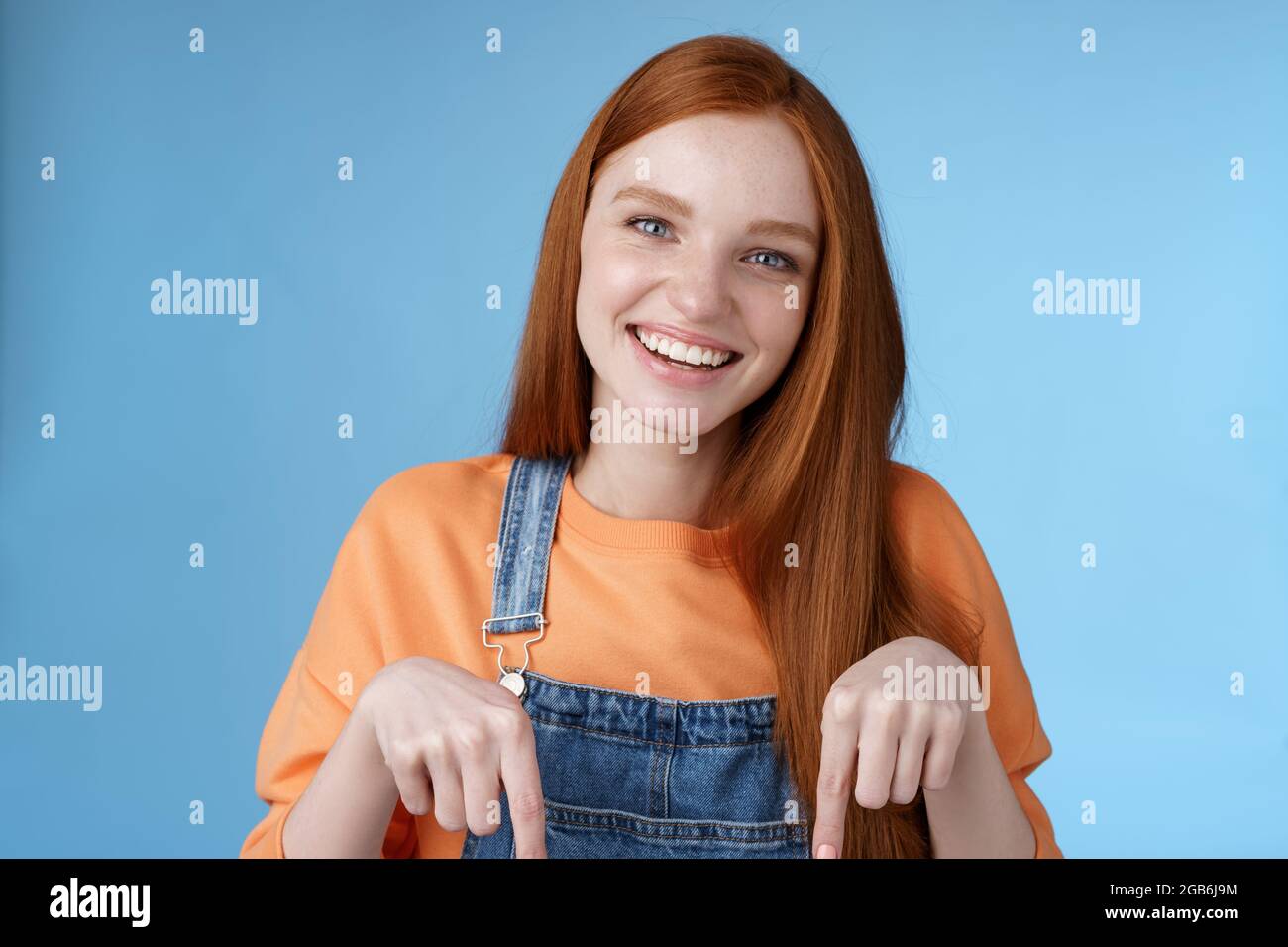 Friendly happy redhead girl smiling lively pretty grin pointing down ...
