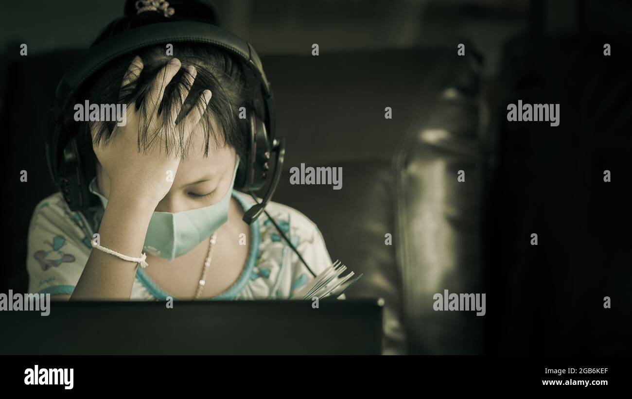 Little girl sit online studying with stress until she has a headache ...