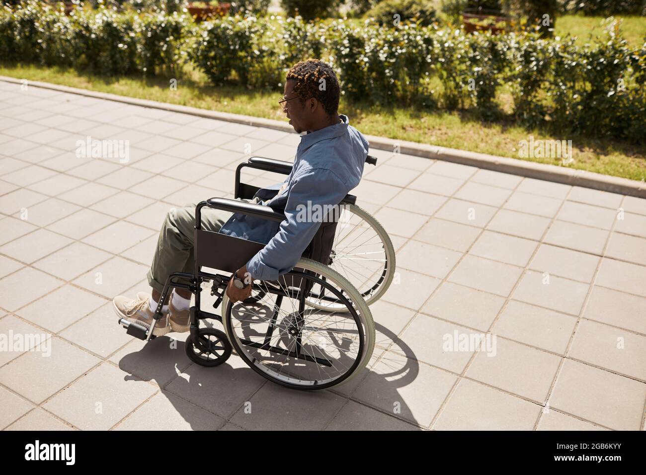 Young Black man with aching legs moving forward in wheelchair over ...