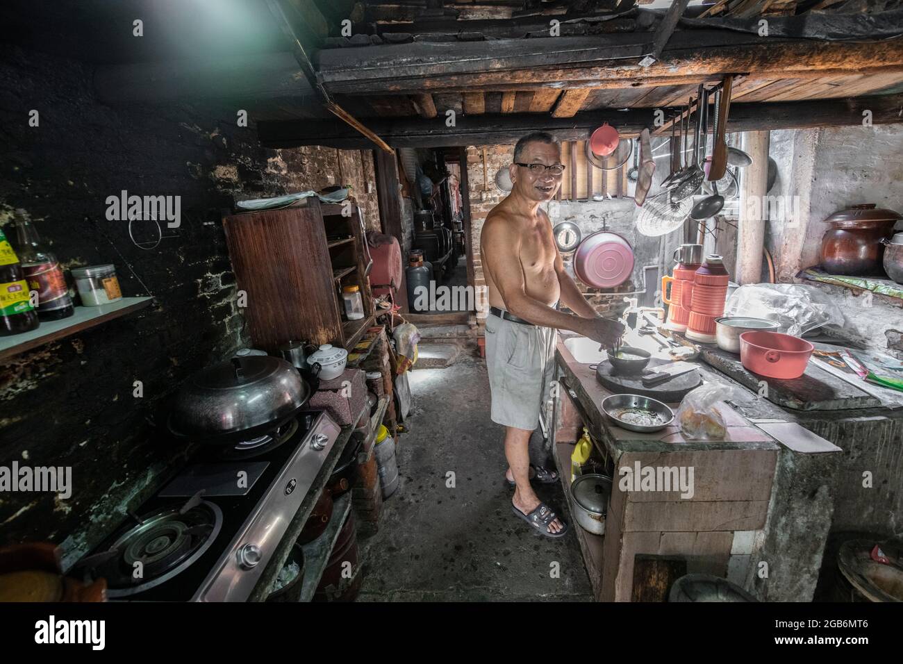 A Chinese man cooks in the kitchen of his house in a village in China ...