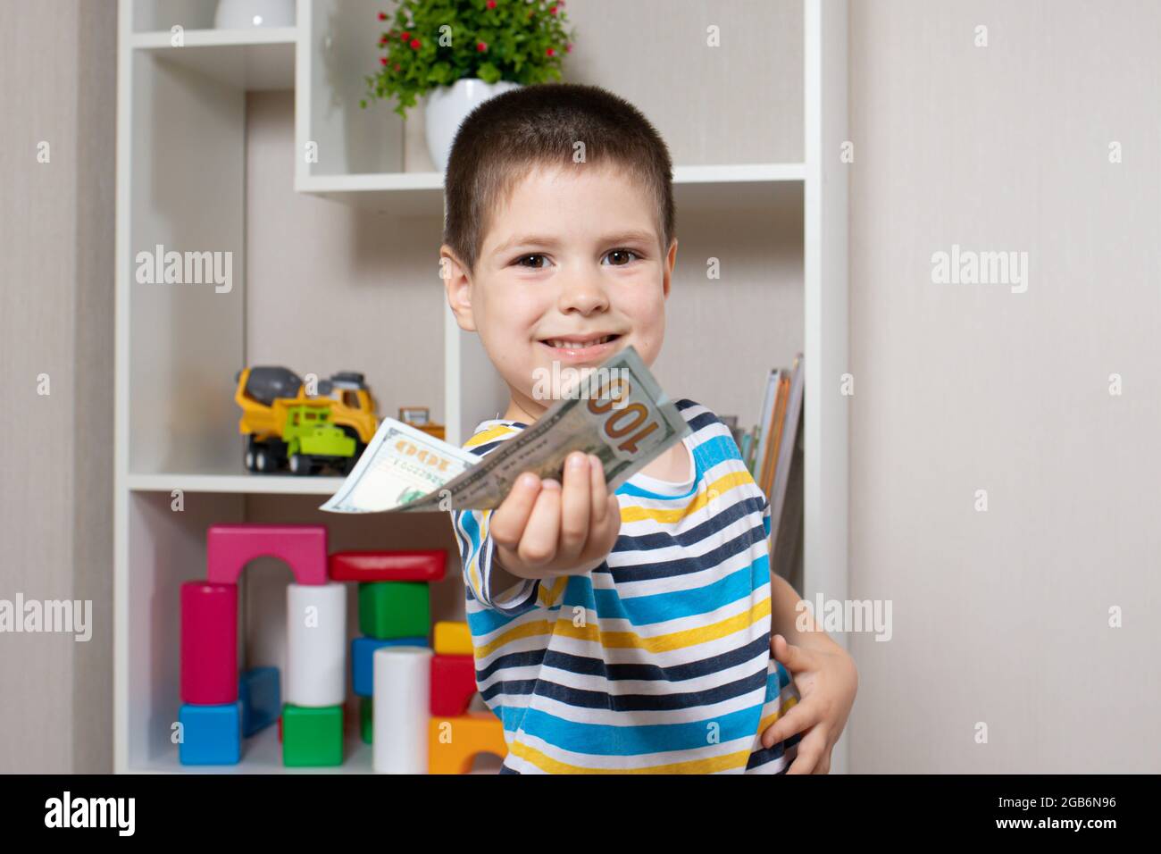 A young child boy of 4 years stretches out his hand with dollar bills ...