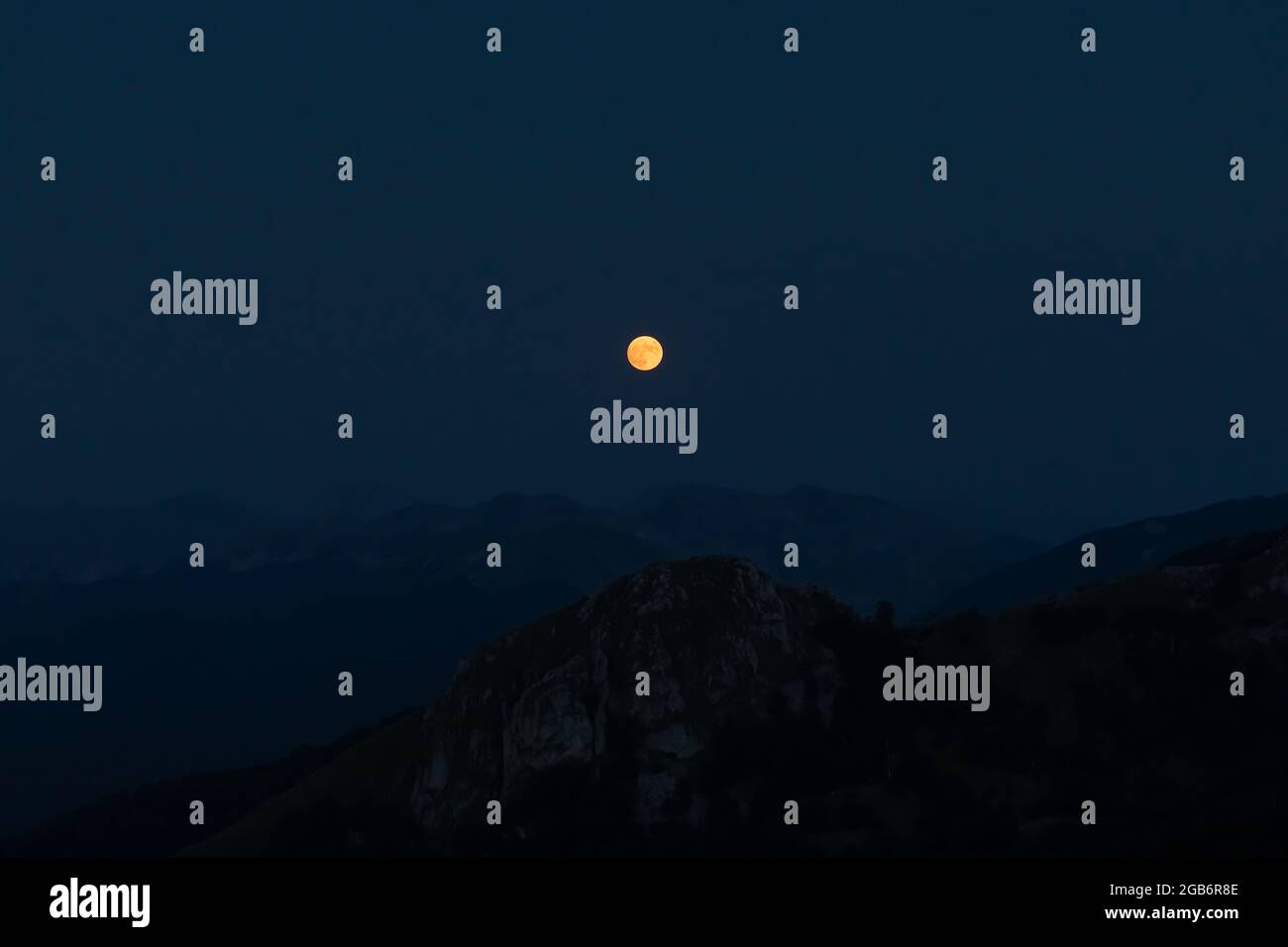 Splendid full red moon rises over the mountain ridges of the Apennines ...