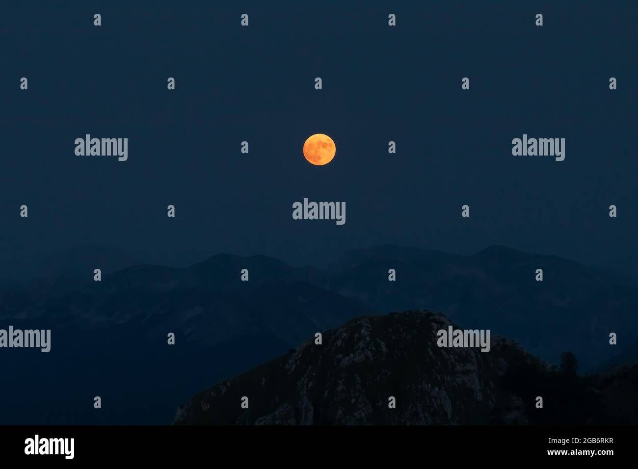 Splendid full red moon rises over the mountain ridges of the Apennines ...