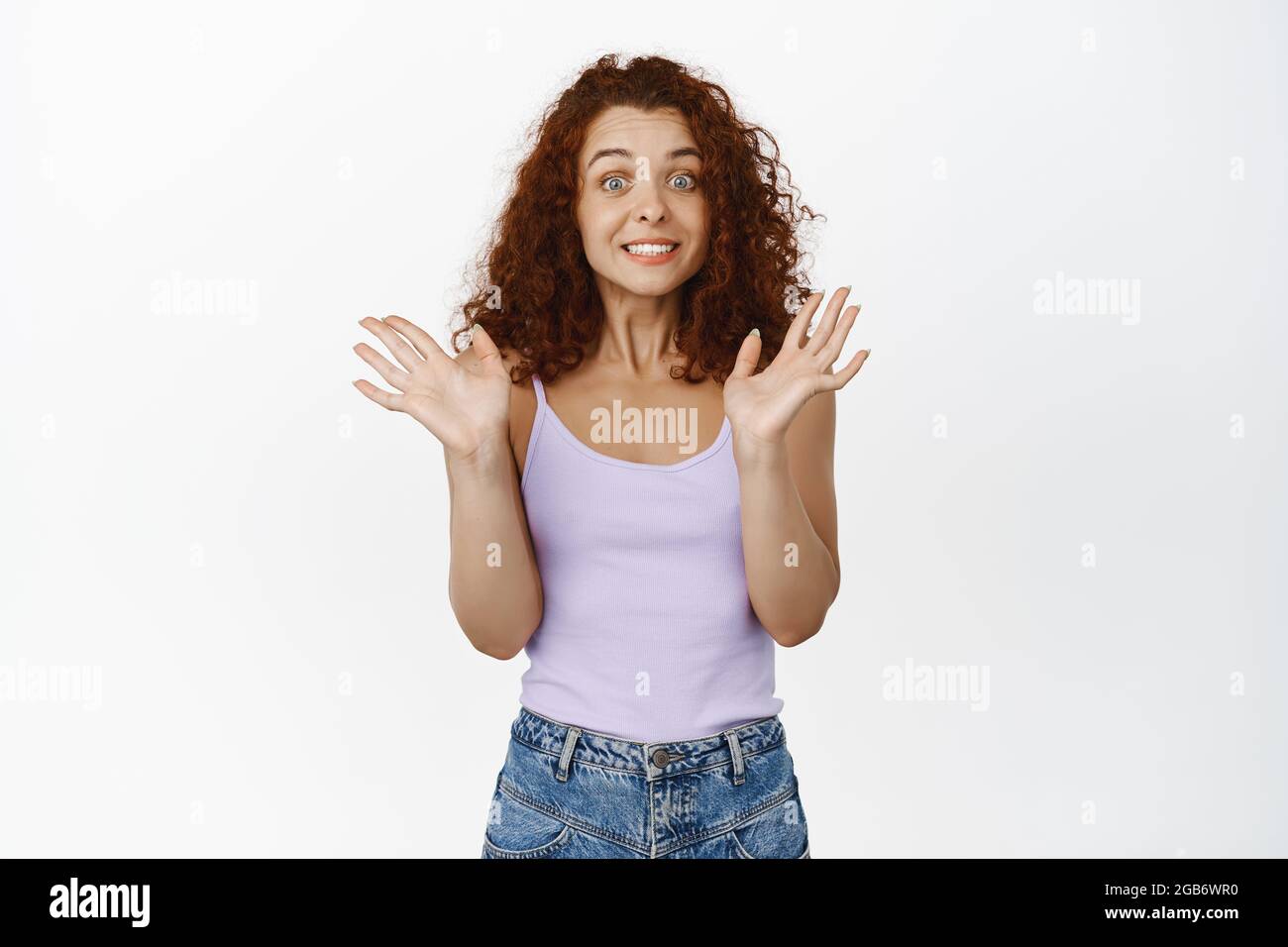 Image of smiling silly redhead girl raising hands up to say sorry ...