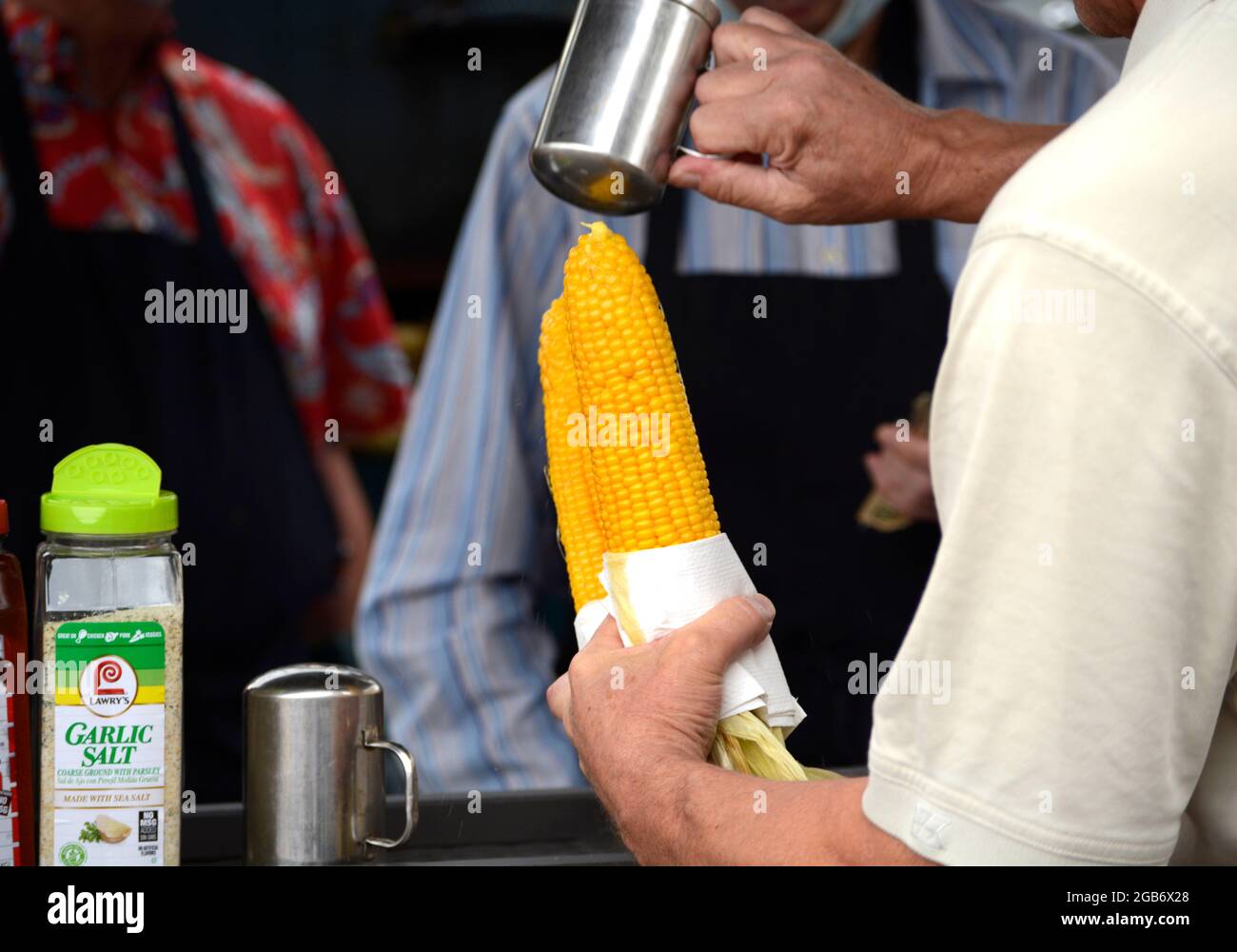 A man buys two ears of roasted corn on the cob at a food stand in Santa ...