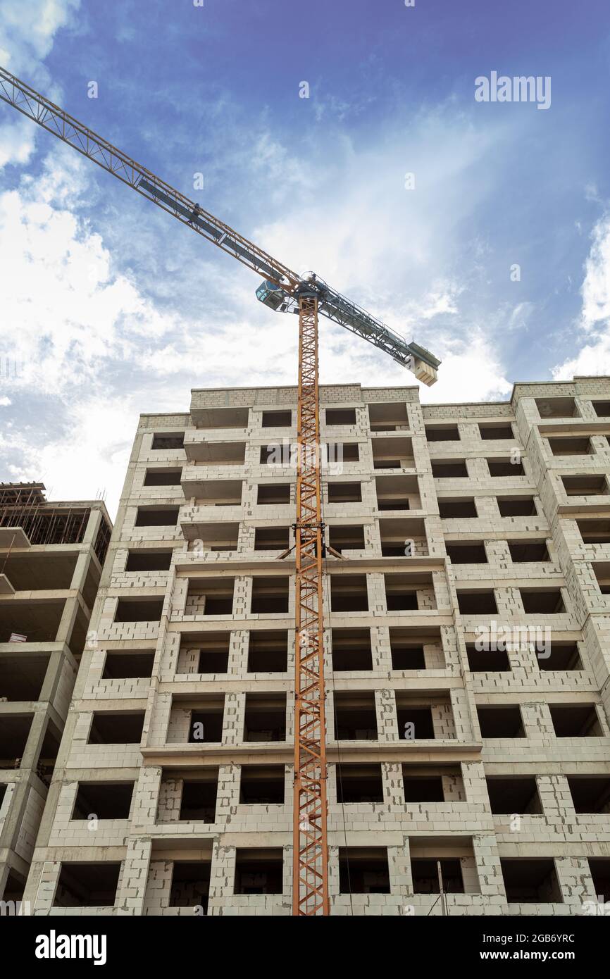 Multi-storey residential building under construction and crane on a background of blue sky Stock ...
