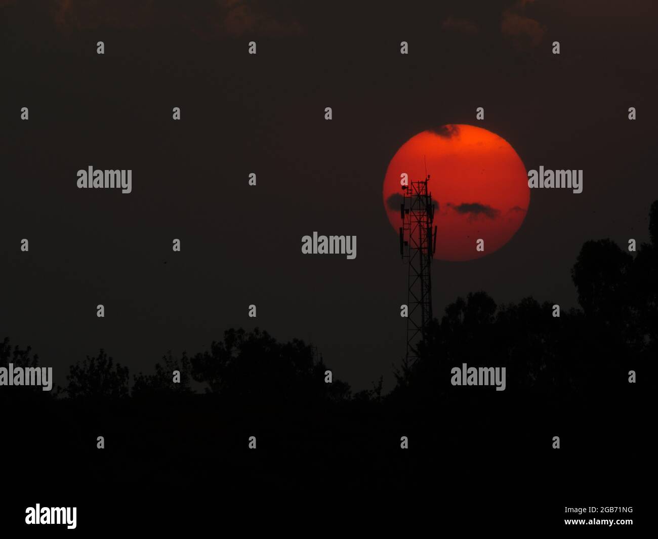Beautiful silhouette of telecommunications tower in front of blazing red sunset, Lake Tana ...