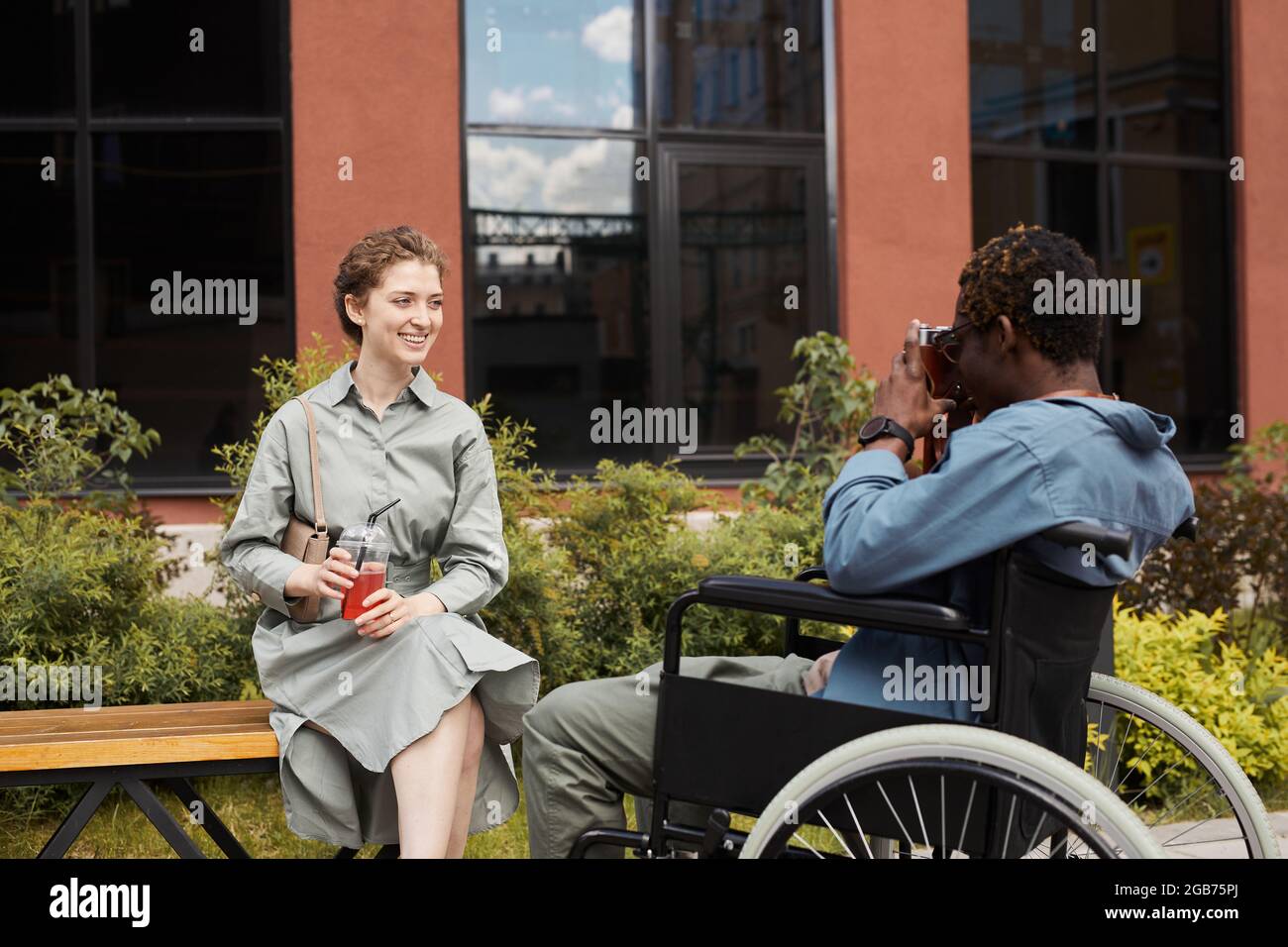 Disabled African-American photographer in wheelchair using camera while ...