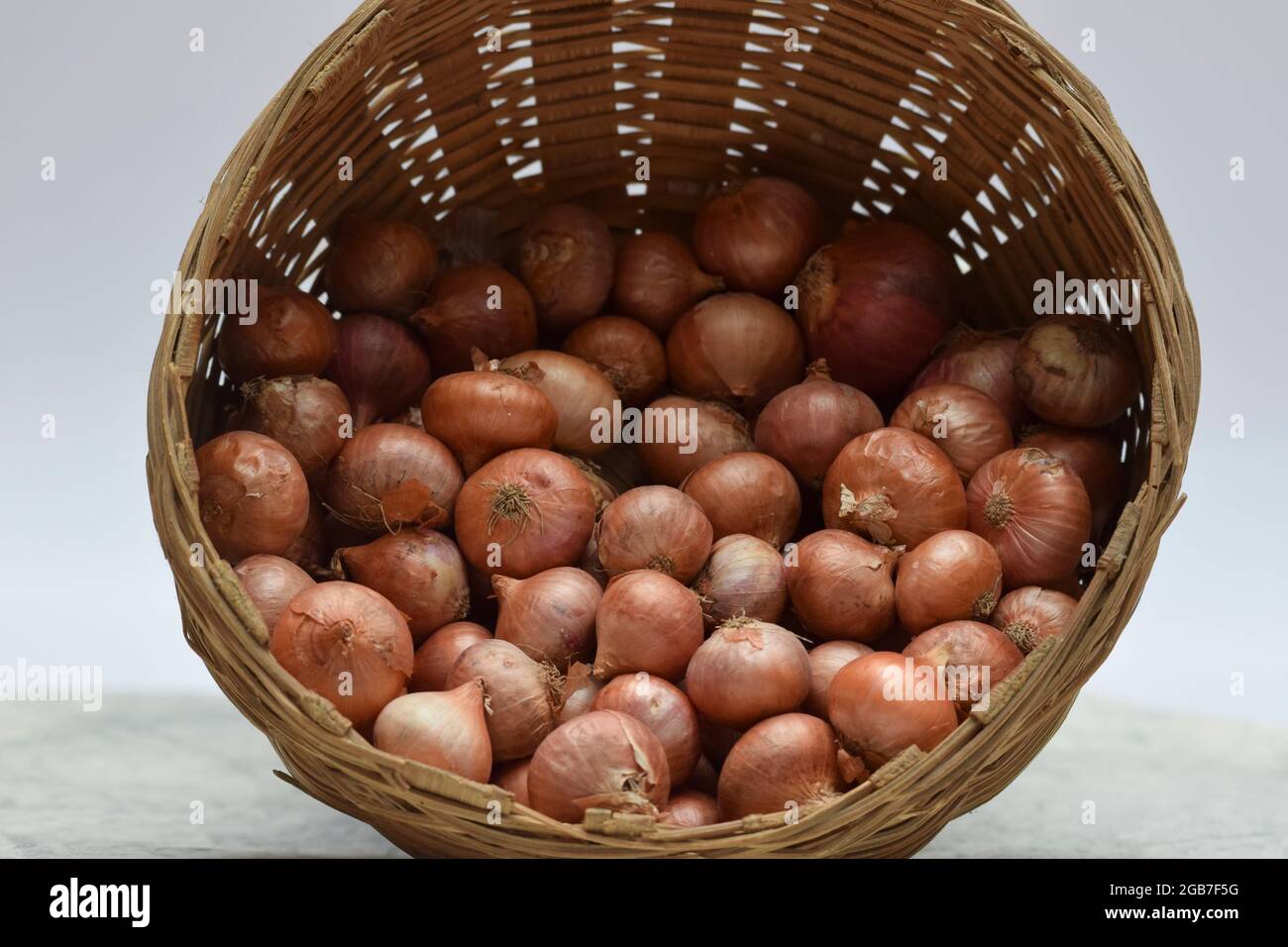 Top view of small onions stored in round brown wicker bamboo basket in ...
