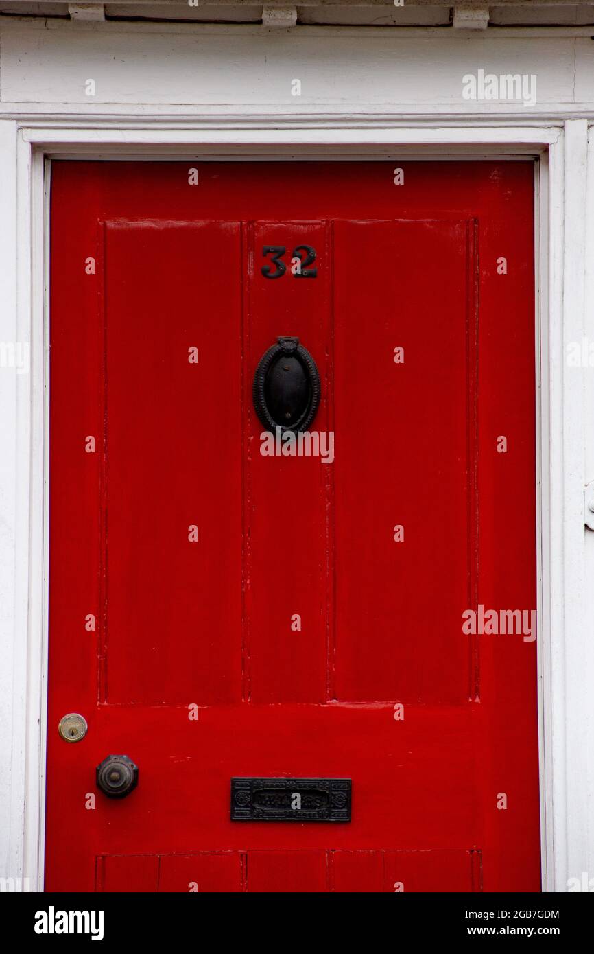 The house number 32 on a red wooden painted front door frame in ...