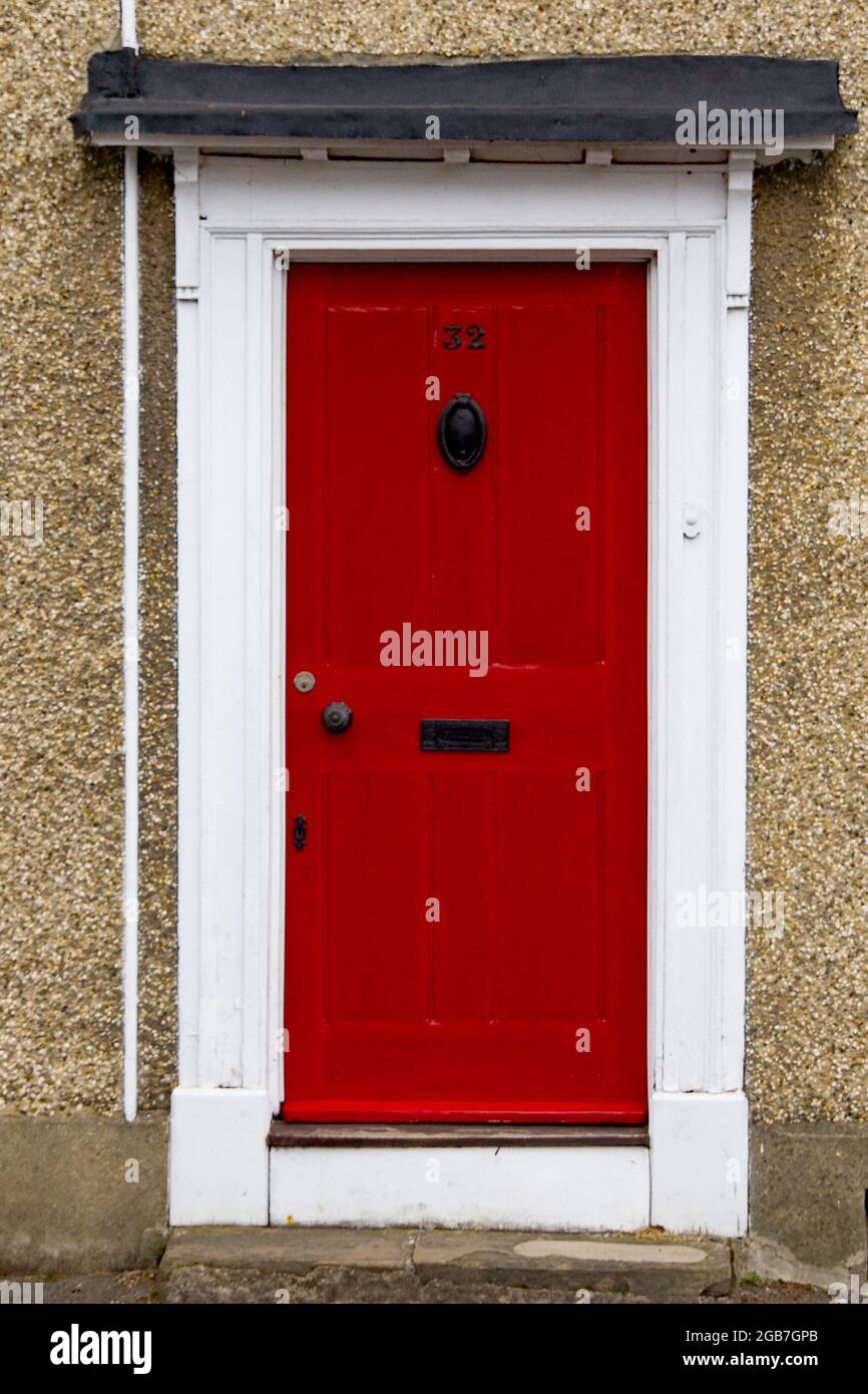 The house number 32 on a red wooden painted front door frame in ...