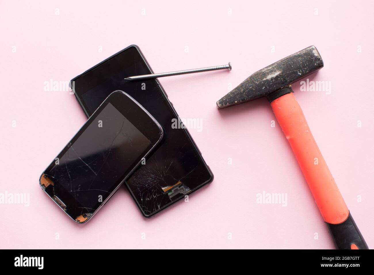 Hammer, nail and mobile phone with broken display on pink background ...