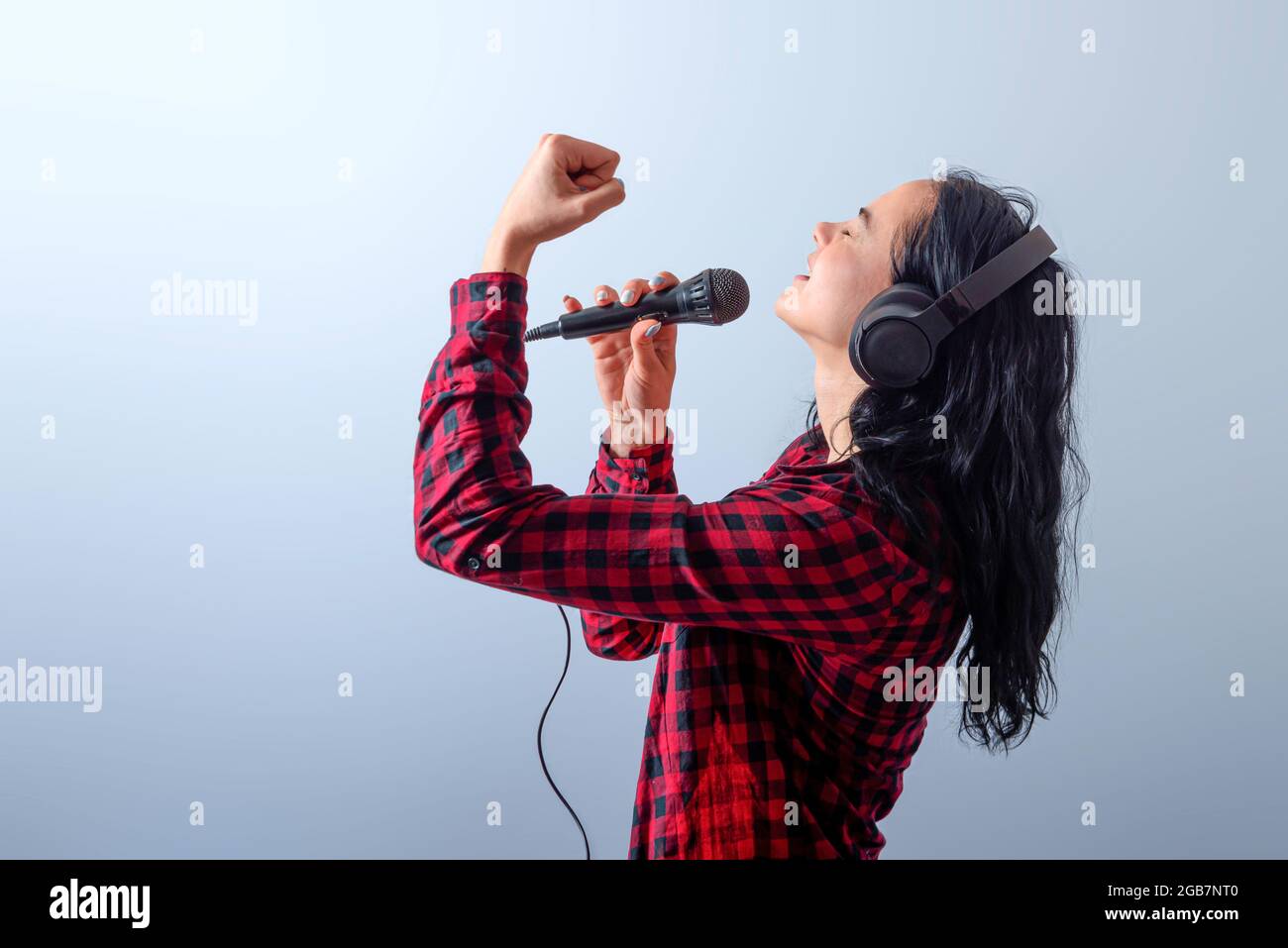 expressive female singing with a microphone and headphones, isolated on ...