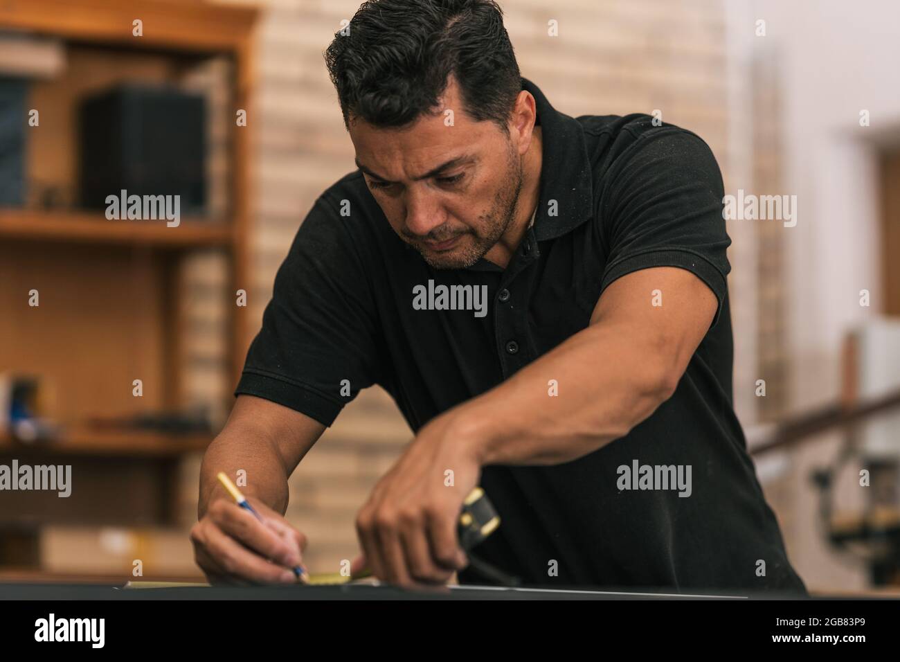 Concentrated man drawing on a surface using a meter in a workshop Stock ...