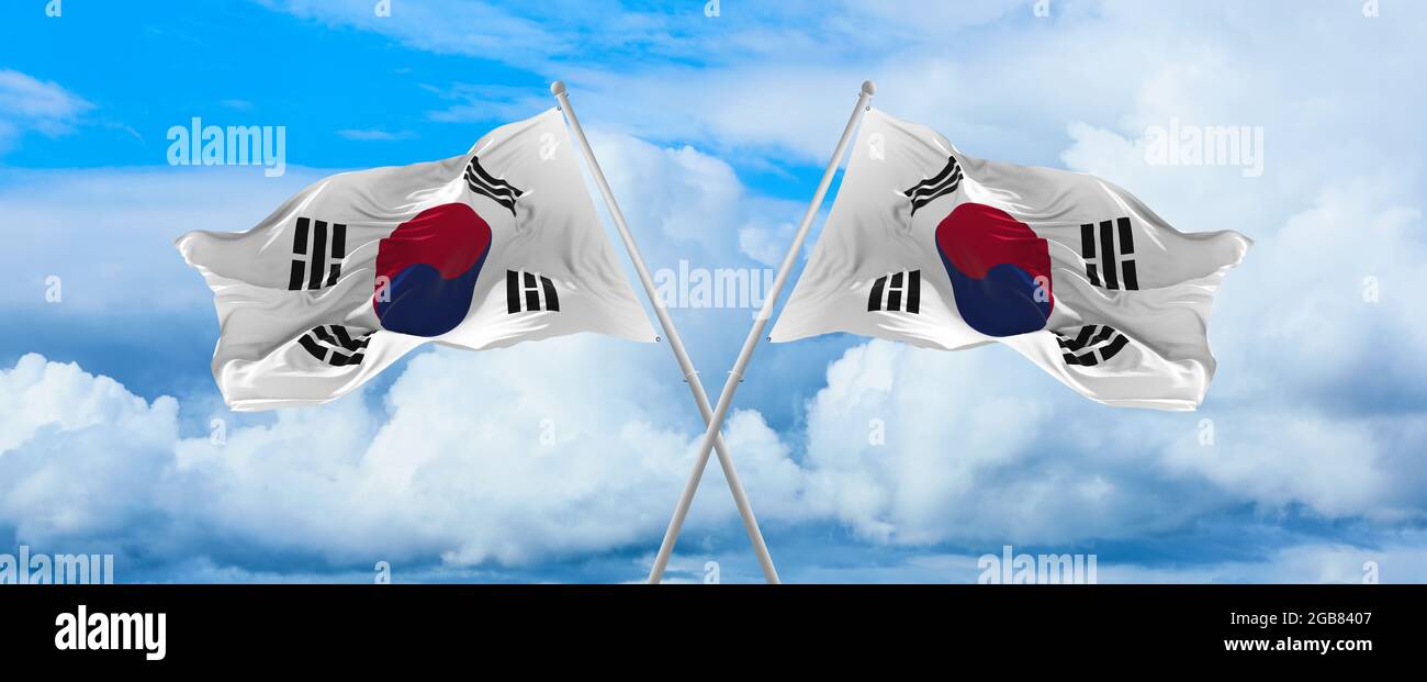 two crossed flags of south korea waving in the wind on flagpoles ...
