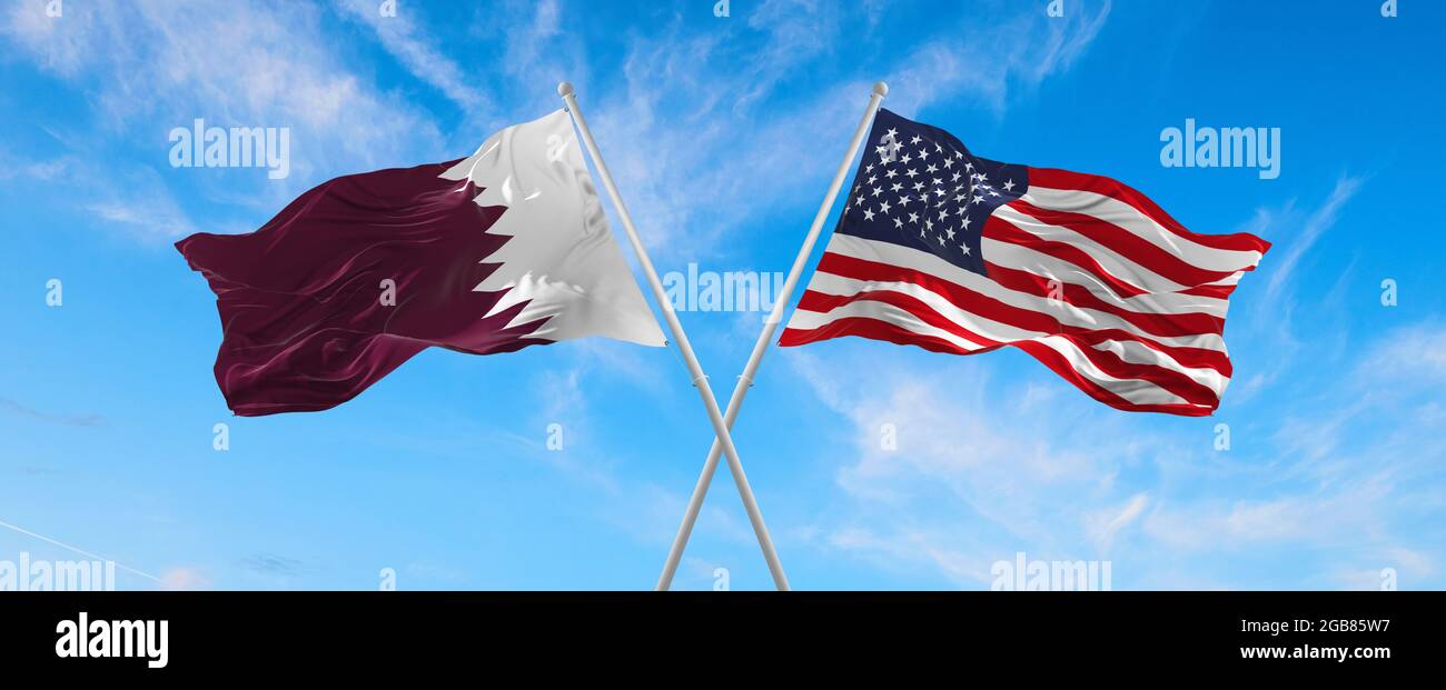 flags of USA and Qatar waving in the wind on flagpoles against the sky ...
