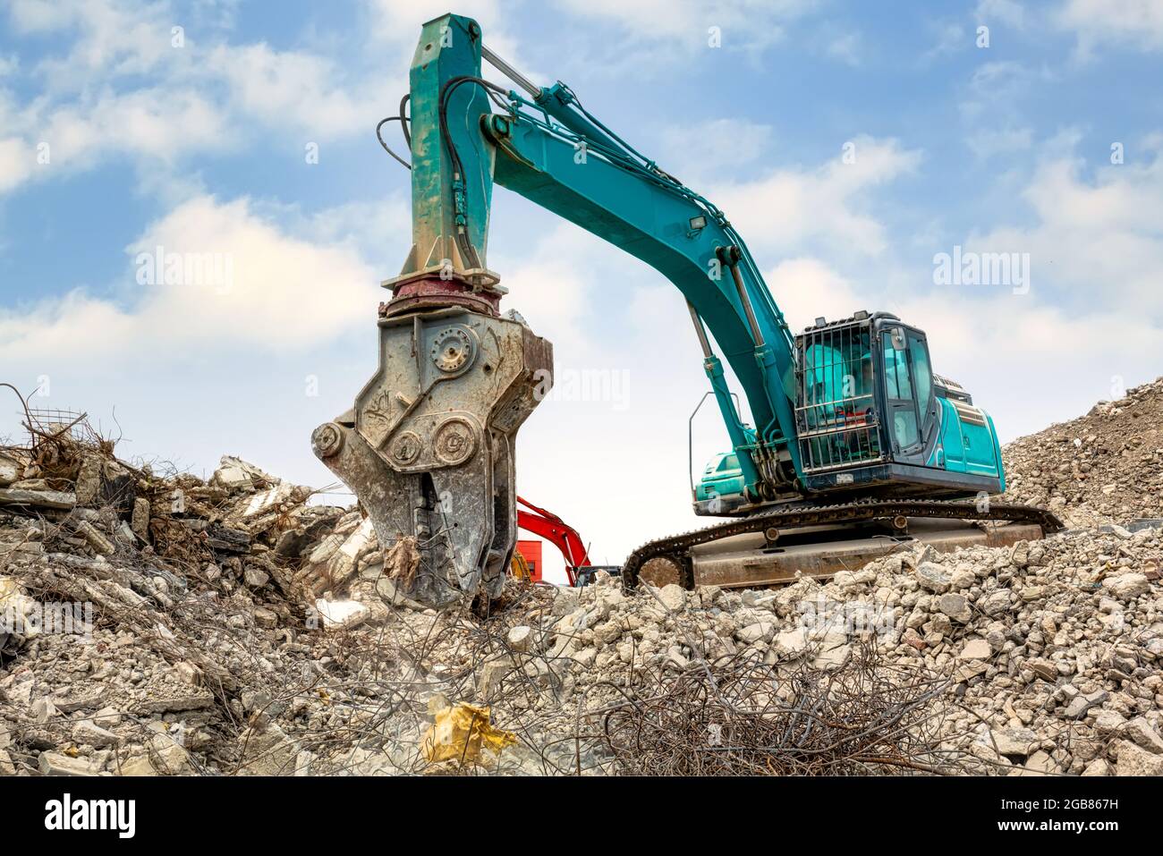 Demolition excavator separating irons and concrete on construction site ...