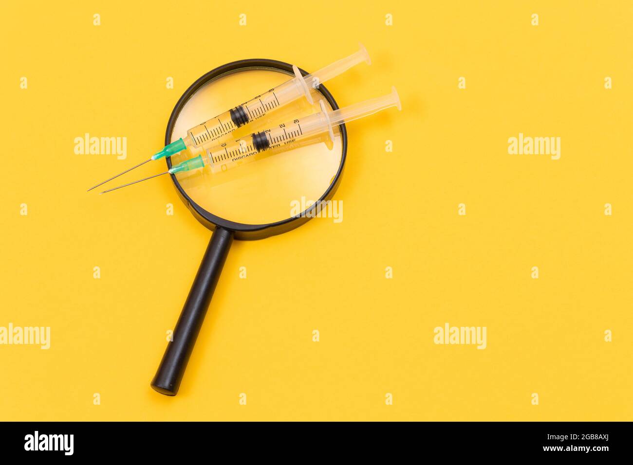 A Magnifier with Medical Syringe Lying on Yellow Table - Vaccination ...