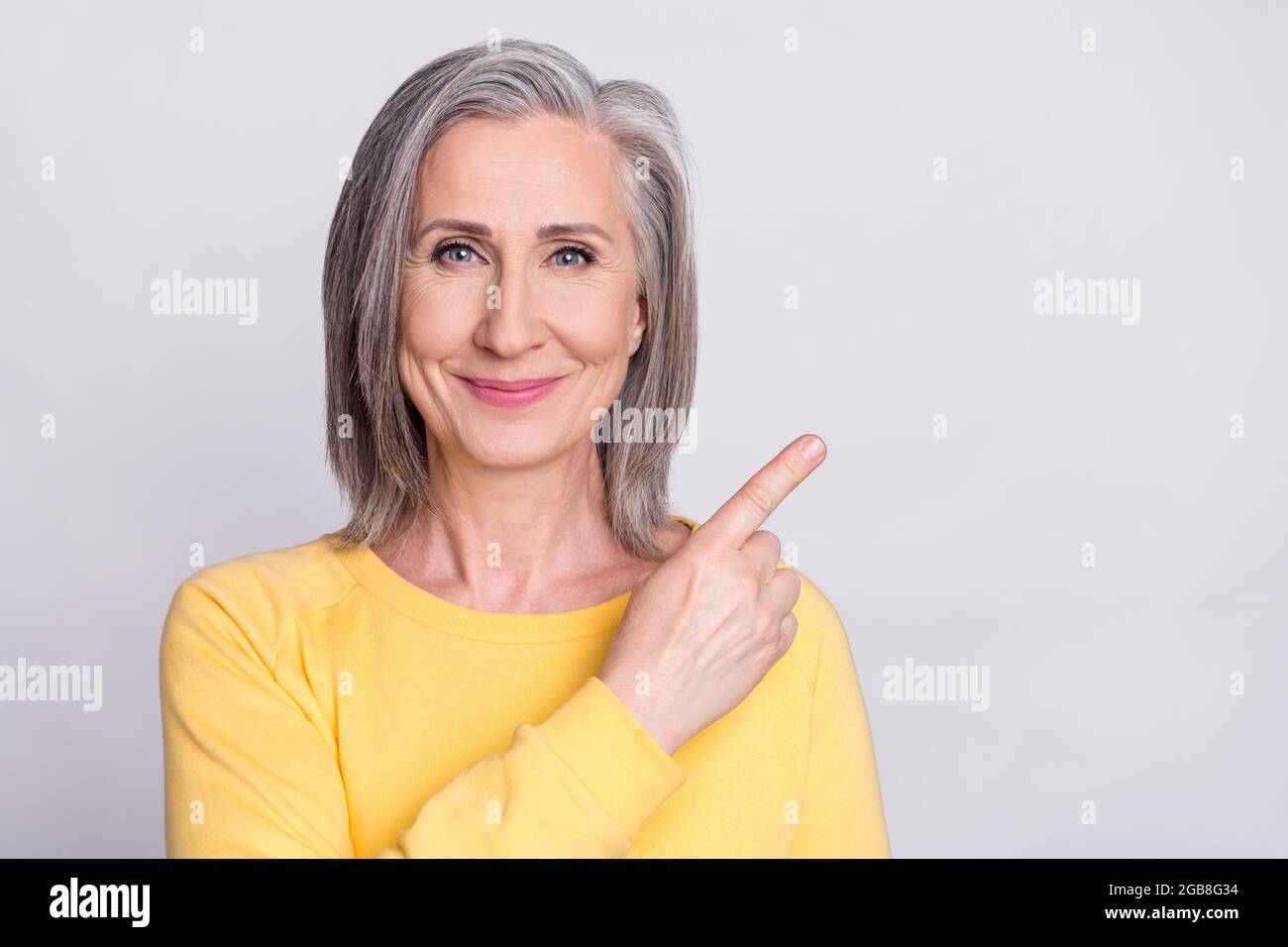 Photo of happy smiling beautiful mature woman point finger copyspace ...