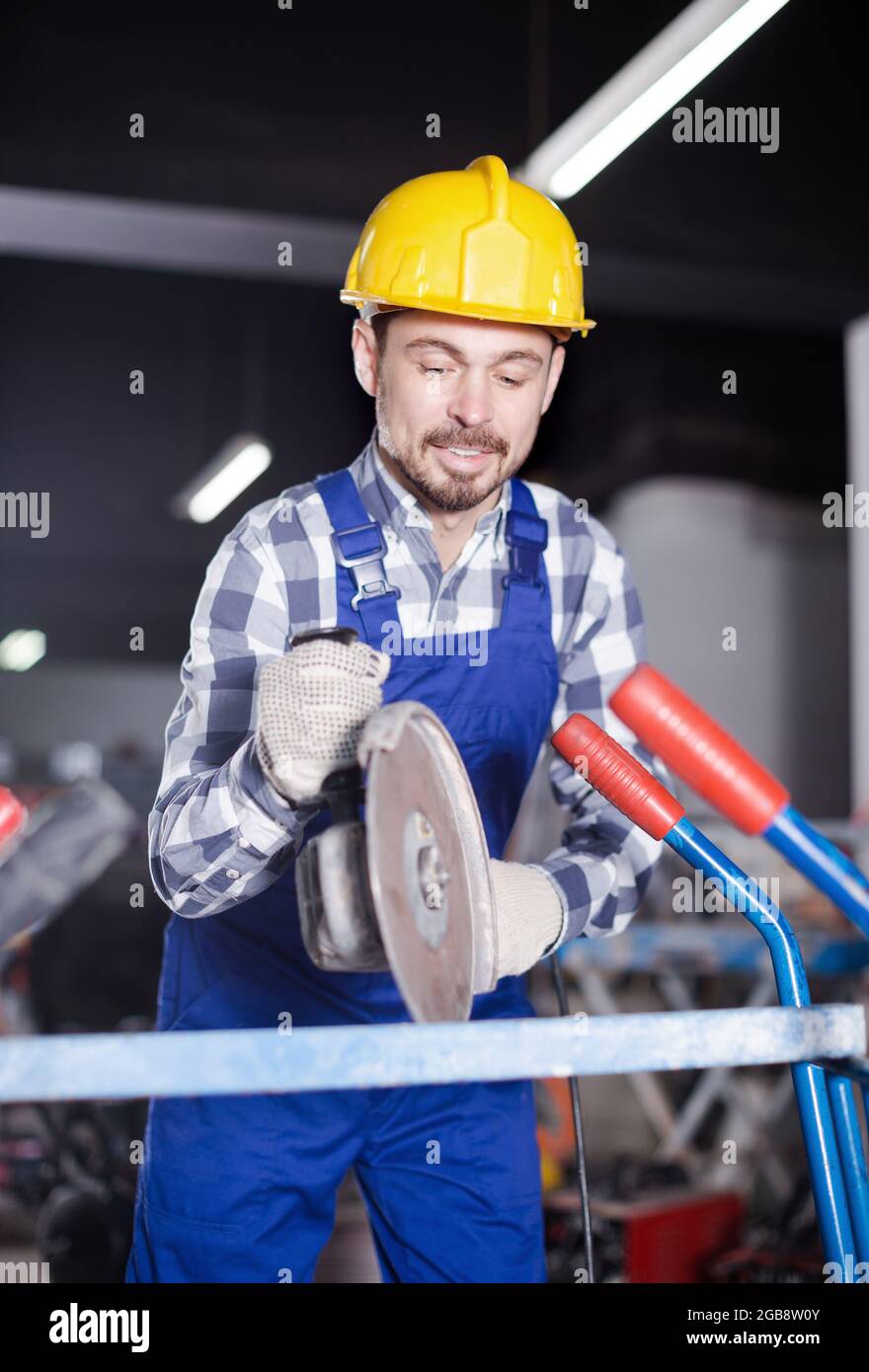 Young positive male using angle grinder for construction Stock Photo ...