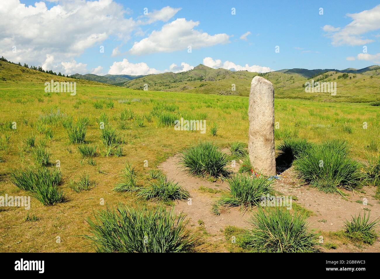 An ancient ritual stone stands in a valley at the foot of a mountain ...
