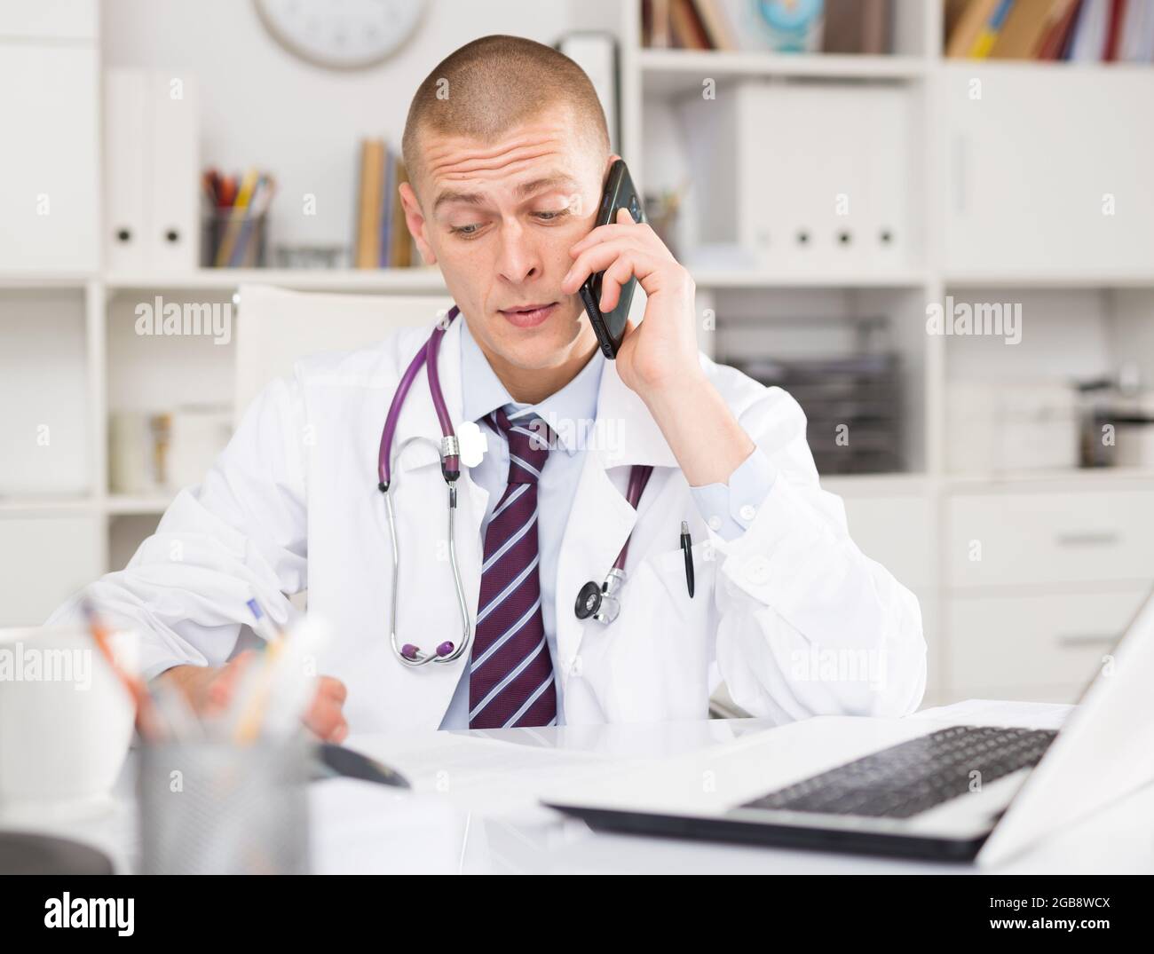 doctor talking on phone and making notes Stock Photo - Alamy