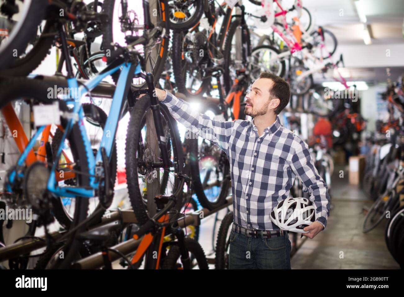 active man in bicycle shop chooses for himself sports bike Stock Photo ...