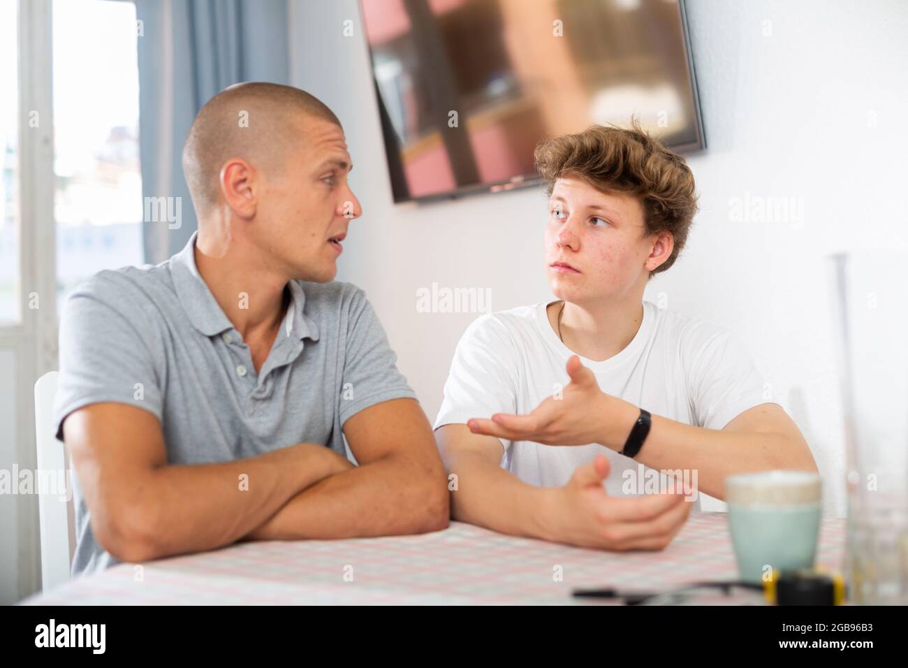 Portrait of teen boy having conversation with man in home Stock Photo ...