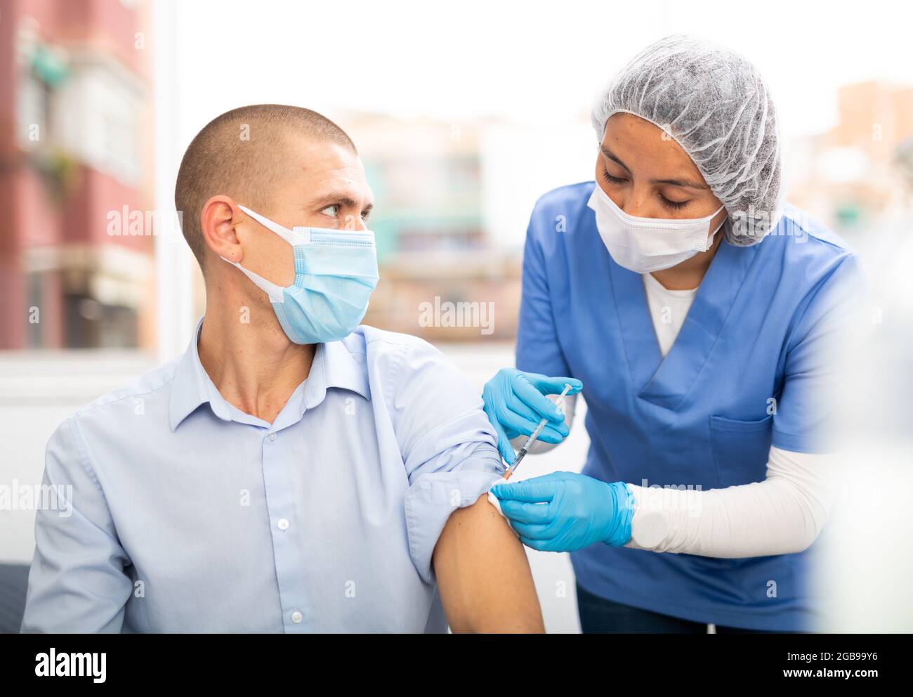 Professional nurse giving vaccine injection to man Stock Photo - Alamy