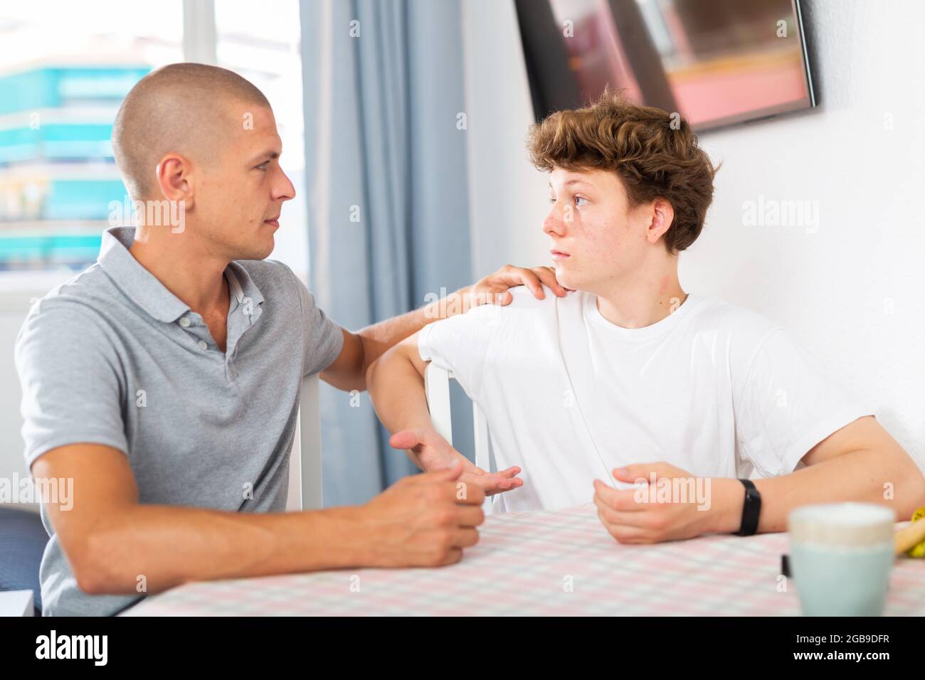 Portrait of teen boy having conversation with man in home Stock Photo ...