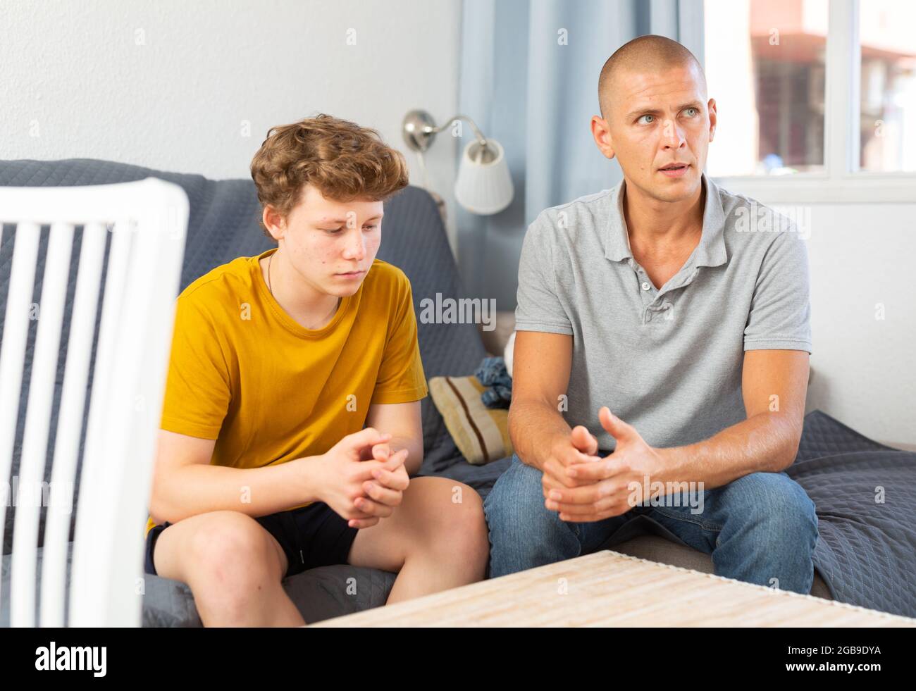 Teenage guy and his father having conversation together Stock Photo - Alamy