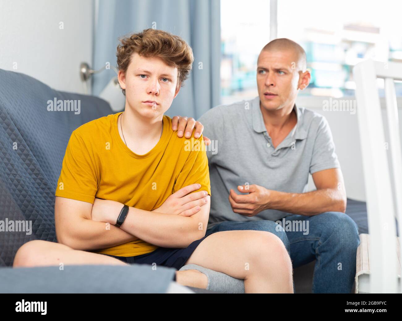 Portrait of father calming upset teenage son after quarrel at home ...