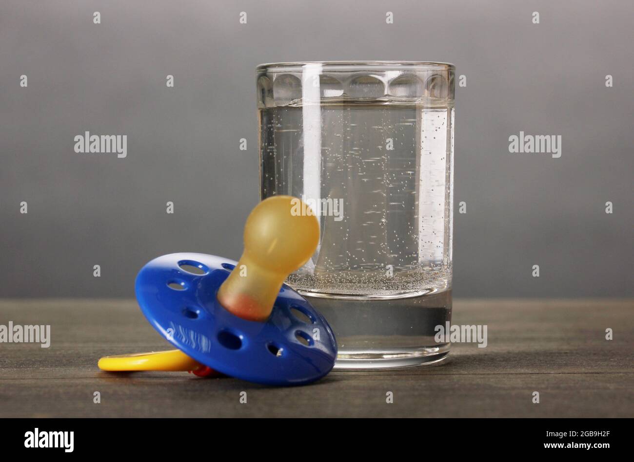 Baby dummy with alcoholic beverage on grey background Stock Photo - Alamy