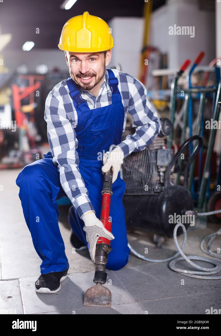 working man practicing his skills with pneumatic drill at workshop ...