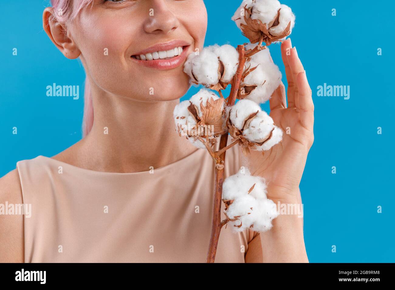 Close up portrait of smiling woman holding sprig with fluffy cotton ...