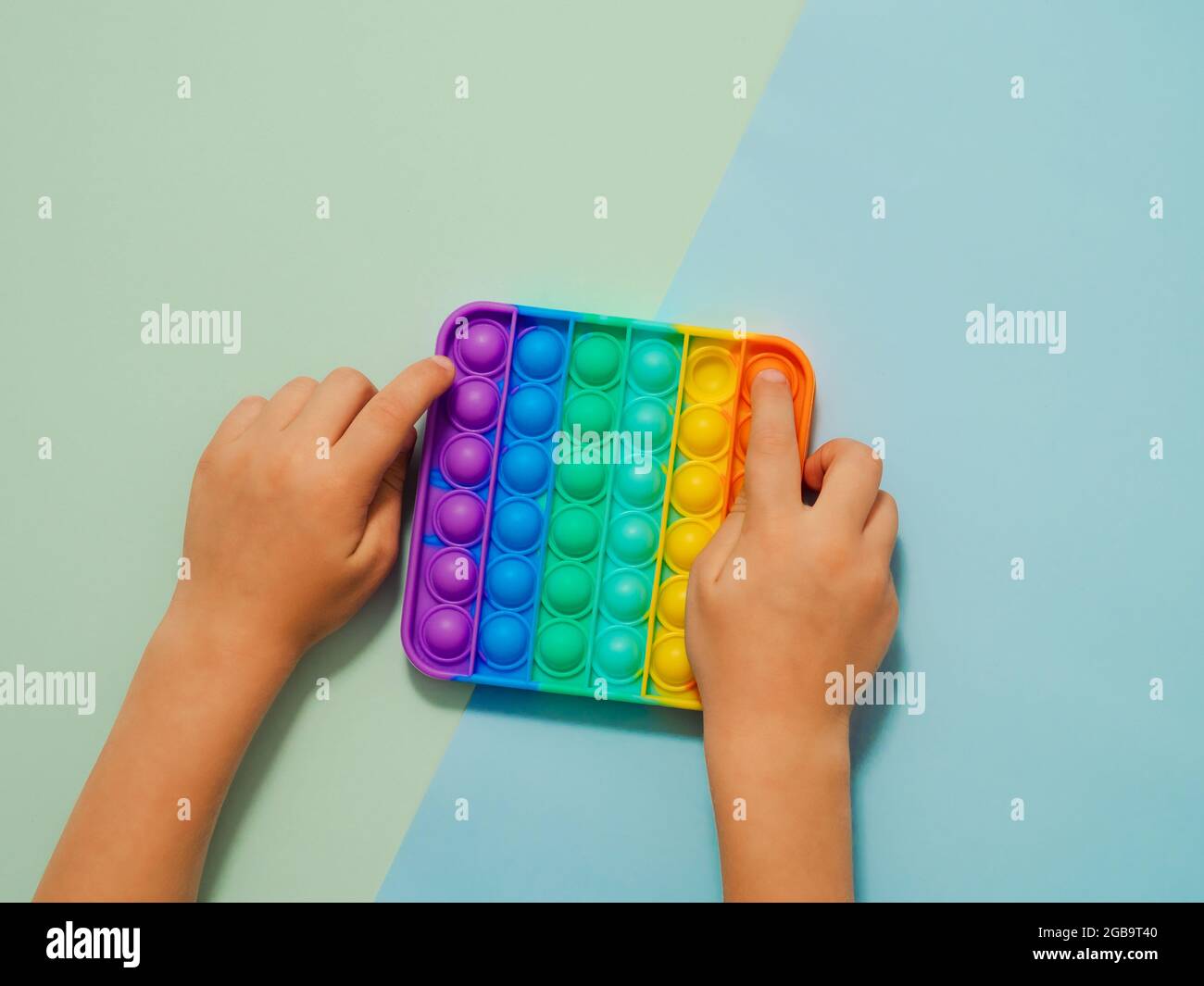 KId hands play popit toy, top view over two-shadows blue background ...