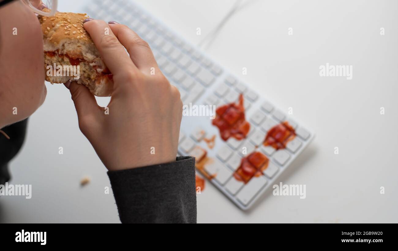 A faceless woman is eating a burger and dripping ketchup on the ...