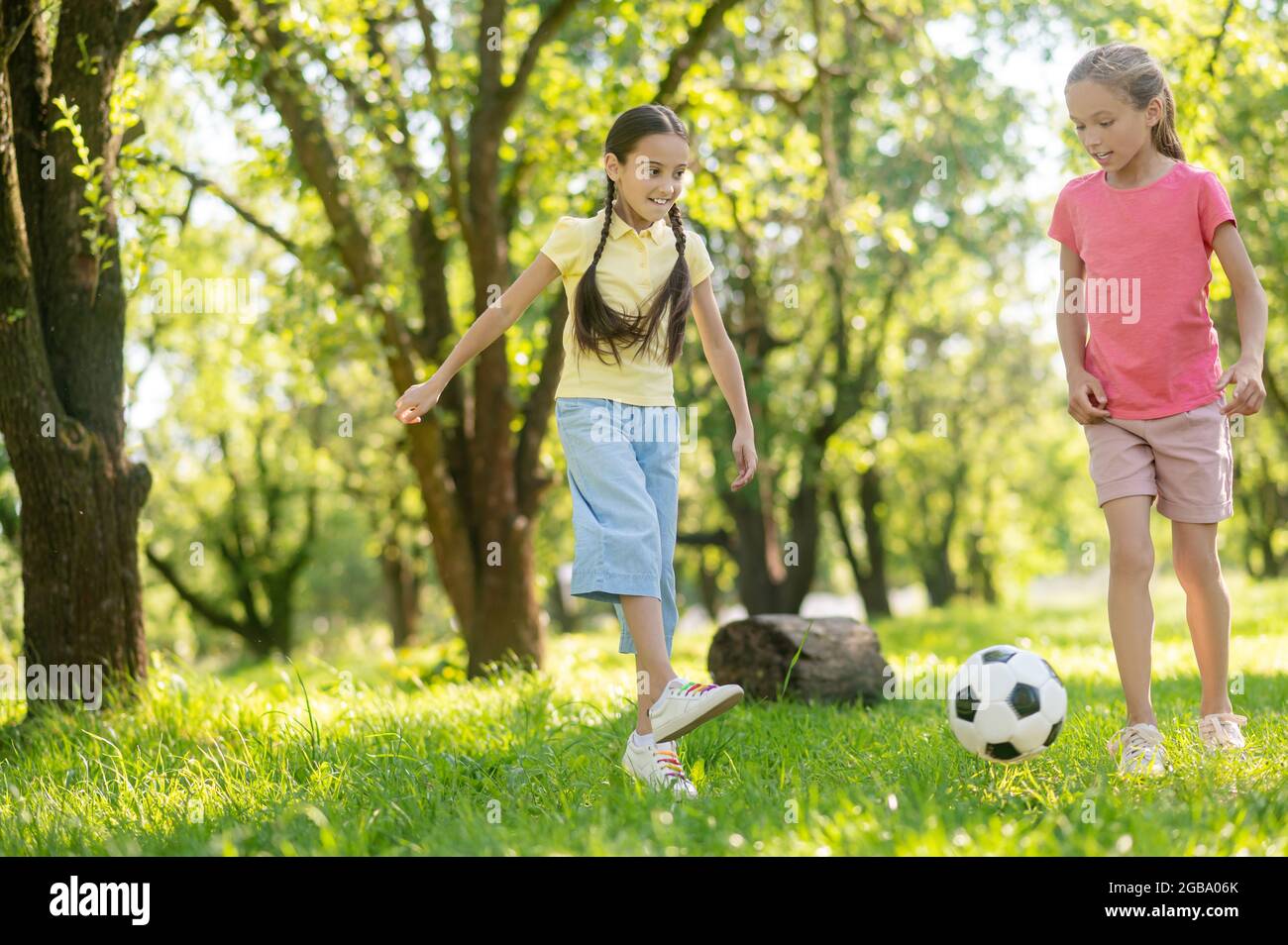 Two younger girlfriends playing soccer on lawn Stock Photo - Alamy