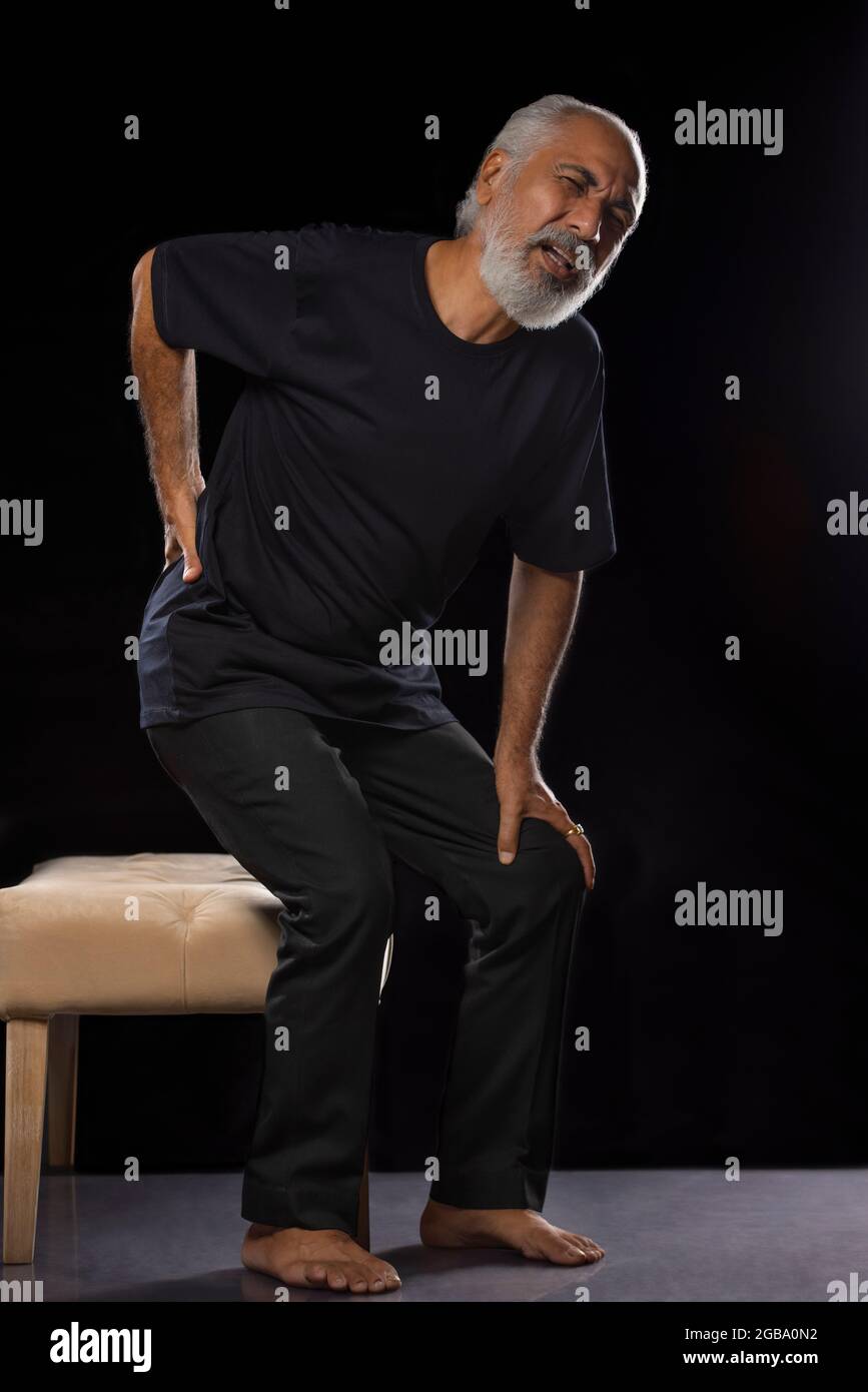 AN OLD MAN EXPERIENCING EXTREME BACK PAIN WHILE TRYING TO GET UP Stock ...