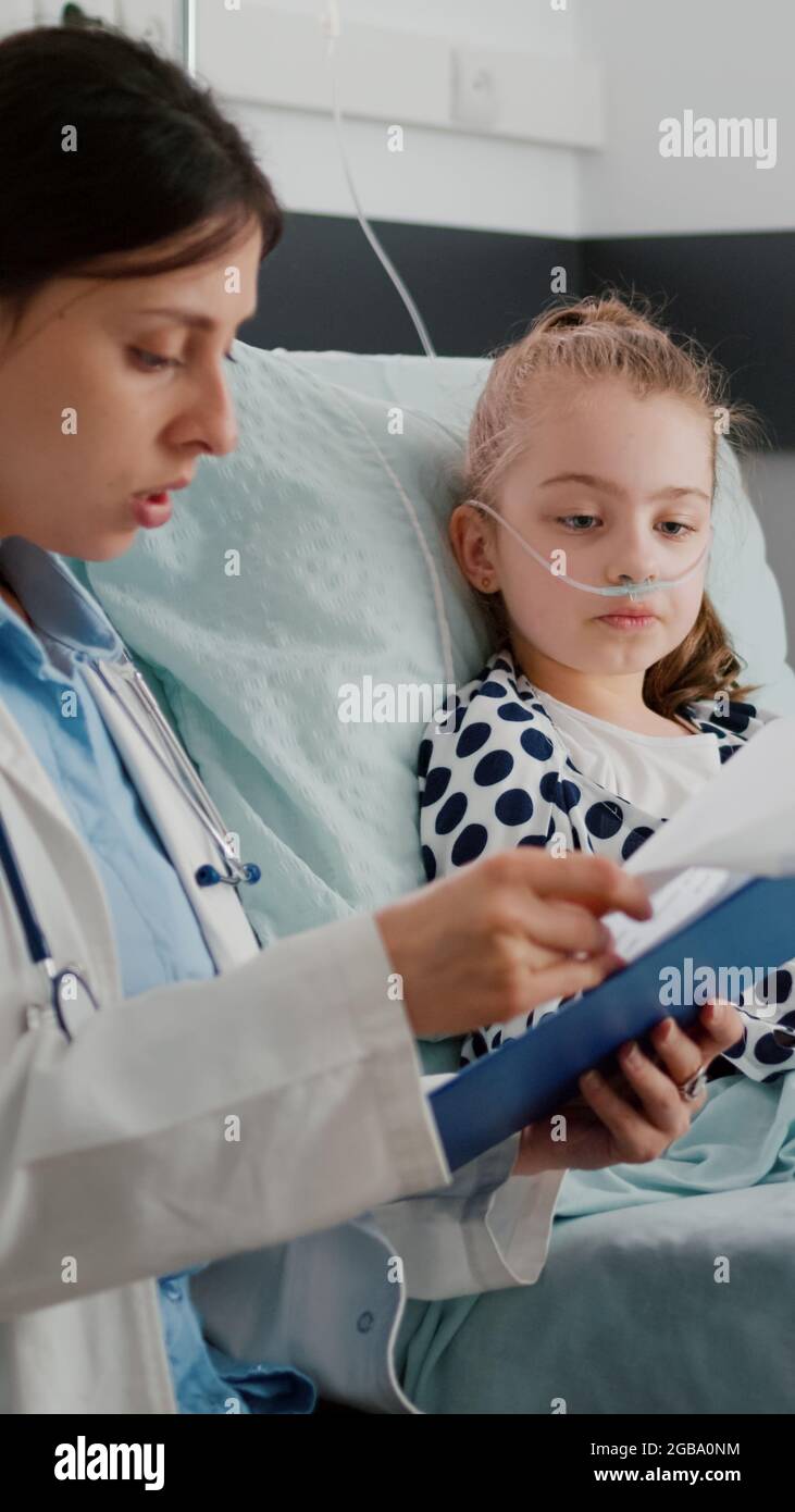Sick child patient wearing oxygen nasal tube resting in bed recovering ...