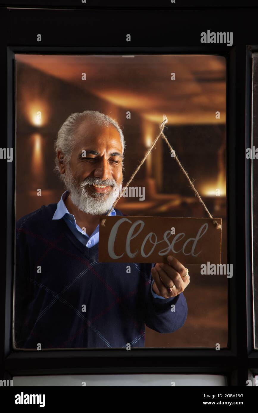 AN OLD MAN HANGING CLOSED SIGN BOARD Stock Photo - Alamy