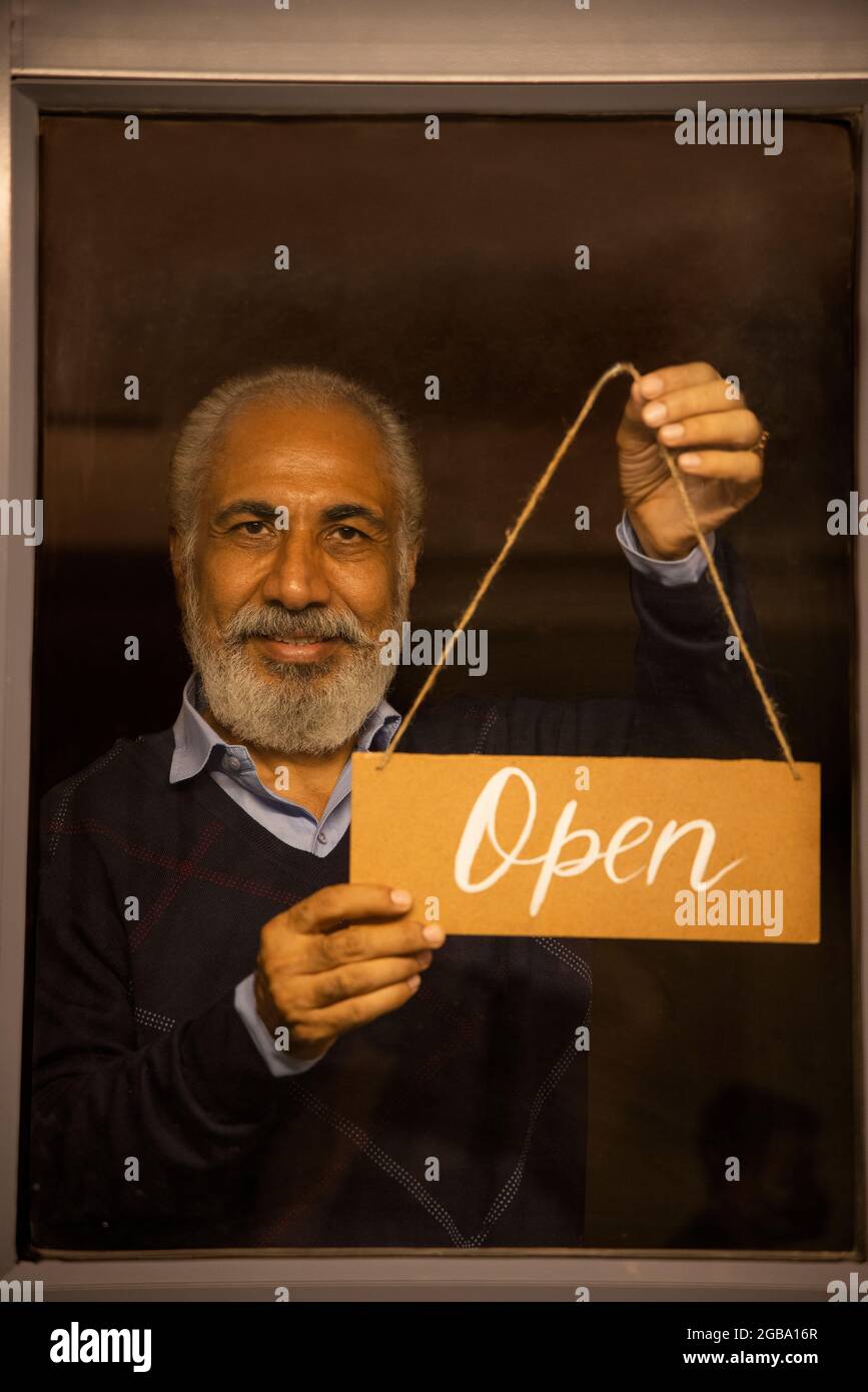 AN OLD MAN HAPPILY HOLDING OPEN SIGN BOARD Stock Photo - Alamy