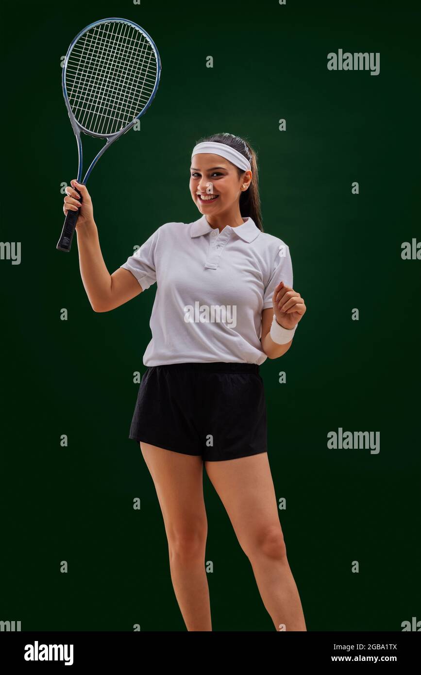 A YOUNG WOMAN PLAYER HAPPILY POSING HOLDING TENNIS RACKET Stock Photo ...