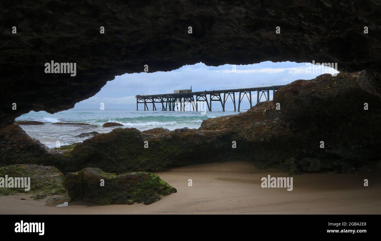 view of a wharf from inside a cave on a beach Stock Photo - Alamy