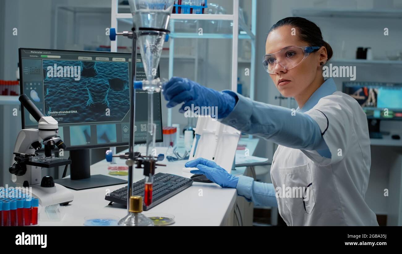 Portrait of doctor using chemical glassware on desk in laboratory for ...