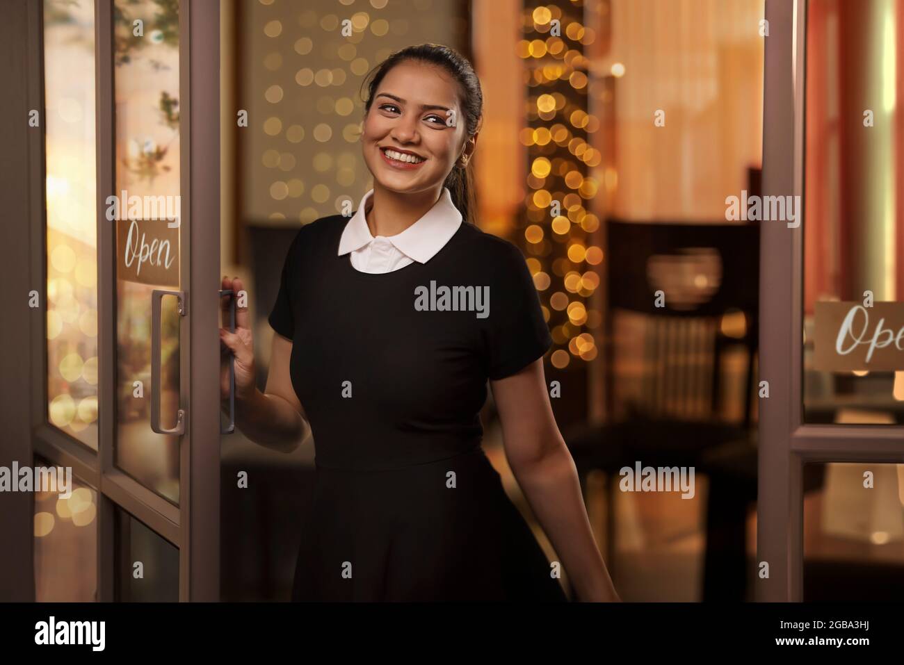 A HAPPY WAITRESS STANDING AND OPENING DOORS OF RESTAURANT Stock Photo ...