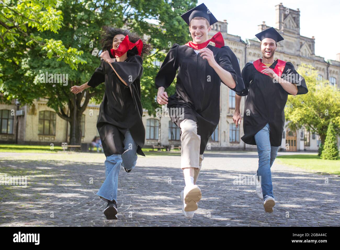 Three graduates running in the park and having fun Stock Photo - Alamy