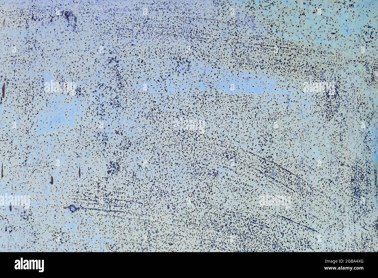 Dots and spots of rust on the blue painted metal wall. Bloated peeling ...